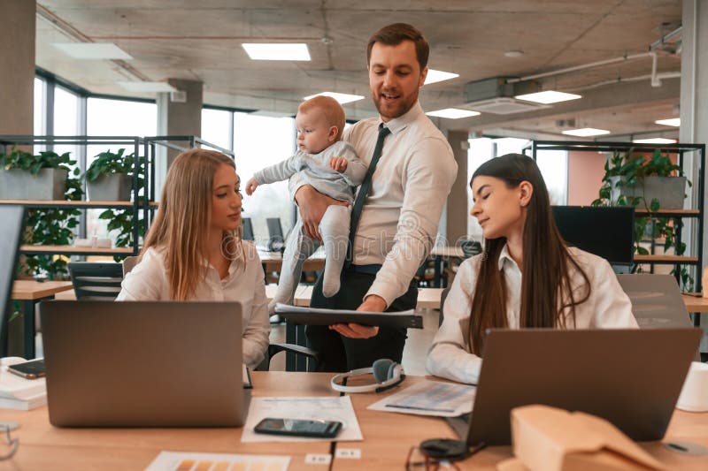 Infant Baby is in the Office Where Group of People are Working Together ...