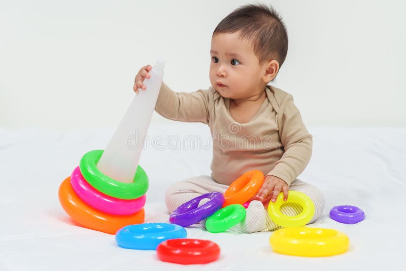 Infant Baby Playing the Pyramid Toy with Colored Rings on Bed Stock ...