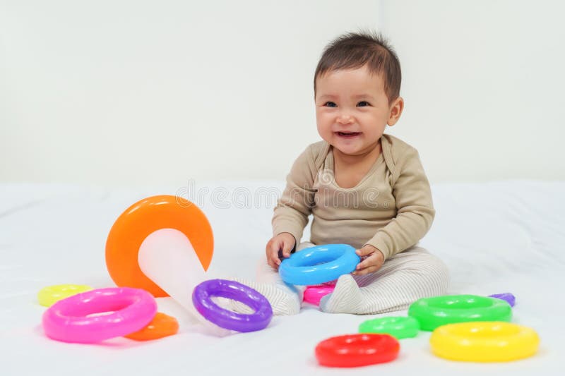 Infant Baby Playing the Pyramid Toy with Colored Rings on Bed Stock ...