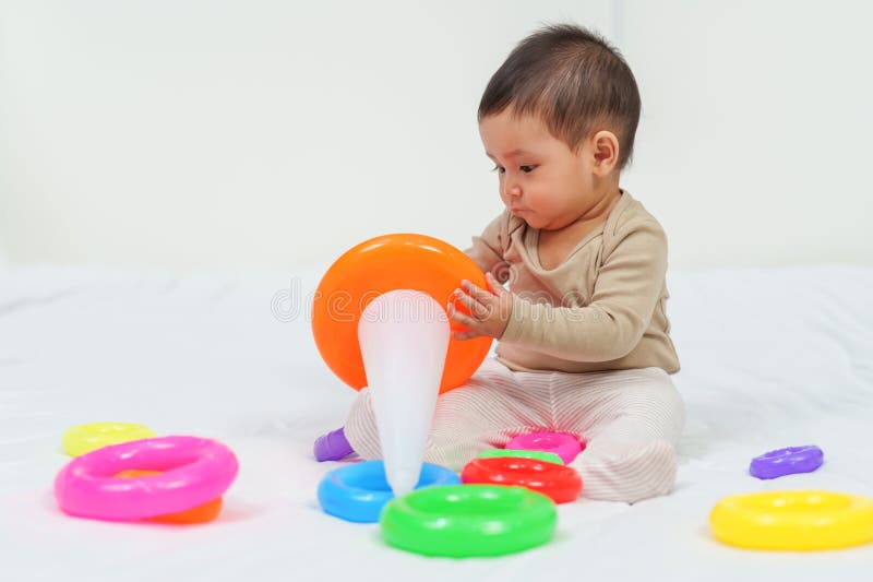 Infant Baby Playing the Pyramid Toy with Colored Rings on Bed Stock ...