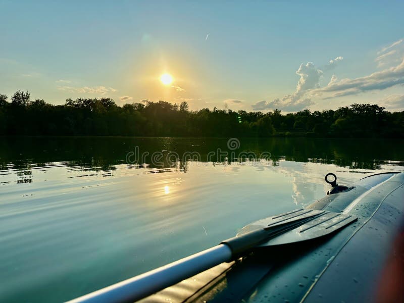 Inflatable Paddle Boat at Sunset on Calm Lake with Reflective Water and ...