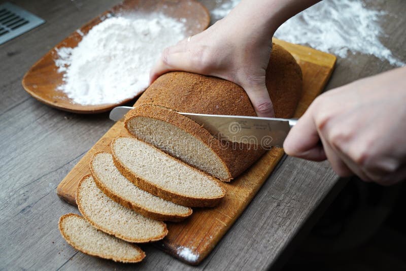 A Woman Cuts a Loaf of Bread on the Table Stock Photo - Image of grain ...