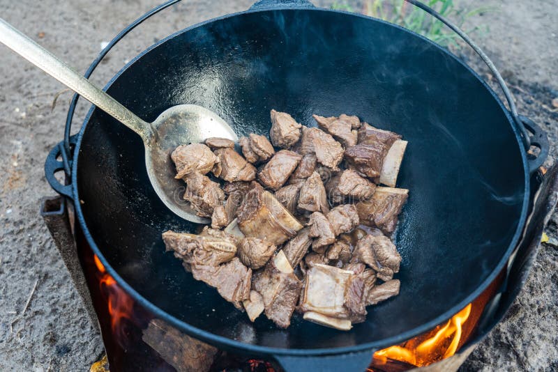The Initial Stage of Cooking Pilaf - Fried Meat in a Cauldron Stock ...