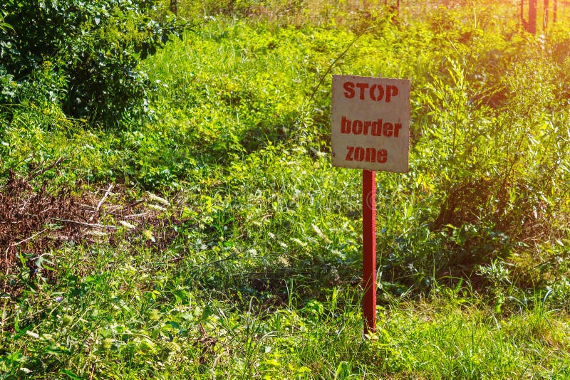 Inscription or Text in English STOP BORDER ZONE. Warning Post about the ...