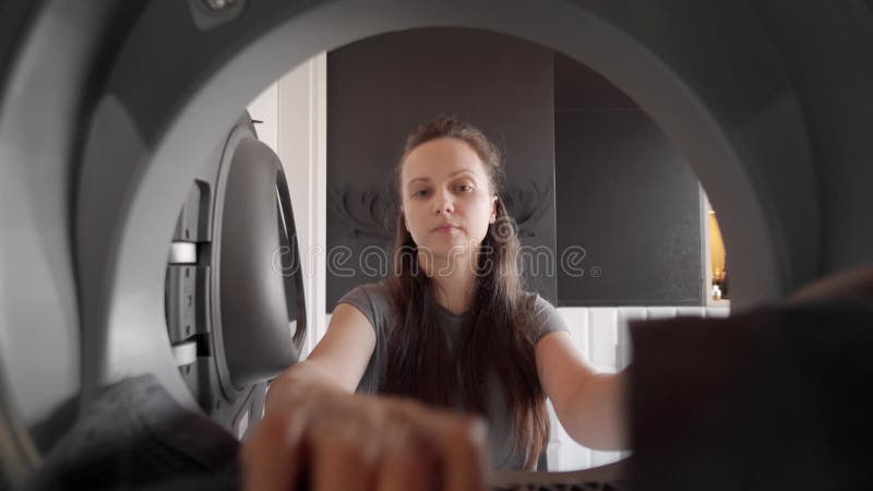 Inside Dryer View of a Woman Loading Laundry into the Dryer. Routine ...