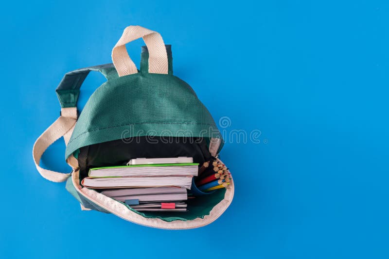 Inside the Green Backpack Lie Books, Notebooks and Pencils on Blue ...
