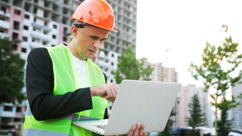 A Man and a Woman with a Laptop in Their Hands in Construction Helmets ...