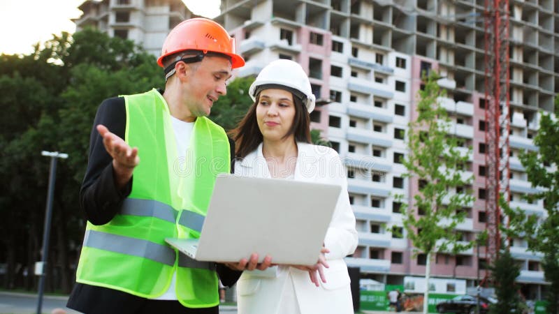A Man and a Woman with a Laptop in Their Hands in Construction Helmets ...