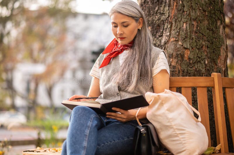 Woman Sitting on a Bench with a Notebook in and Looking Involved Stock ...