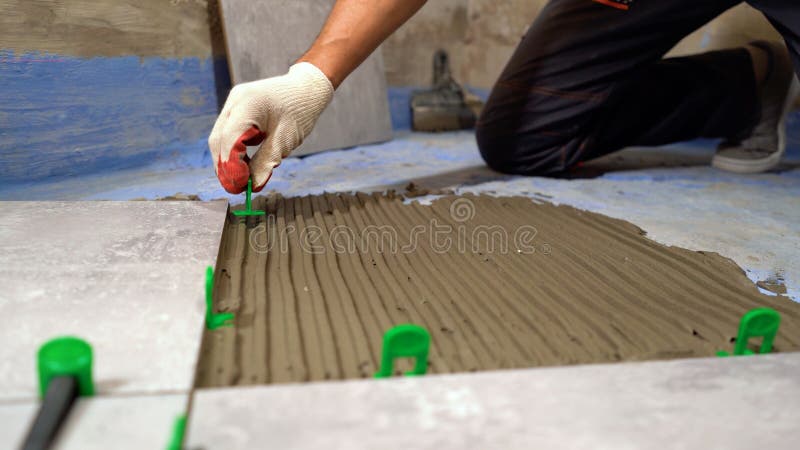 Worker Hands Placing Spacers between Ceramic Floor Tiles. Installing a ...