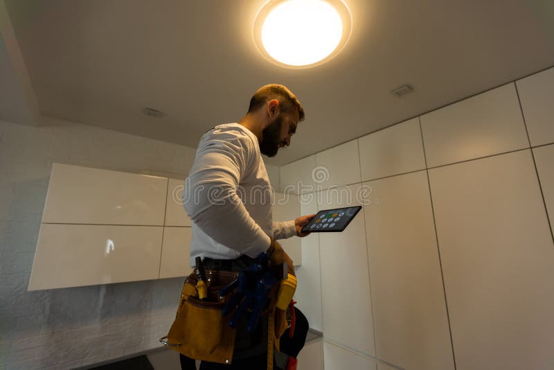 Installation Lighting. Builder is Holding a Tablet in His Hands ...