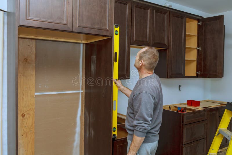 Installation of New Kitchen Cabinets Requires Worker To Hang a Level in ...