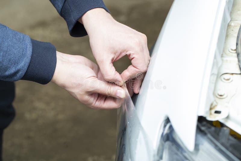 Installation of a Protective Film for Car Paint.the Workers Install a ...