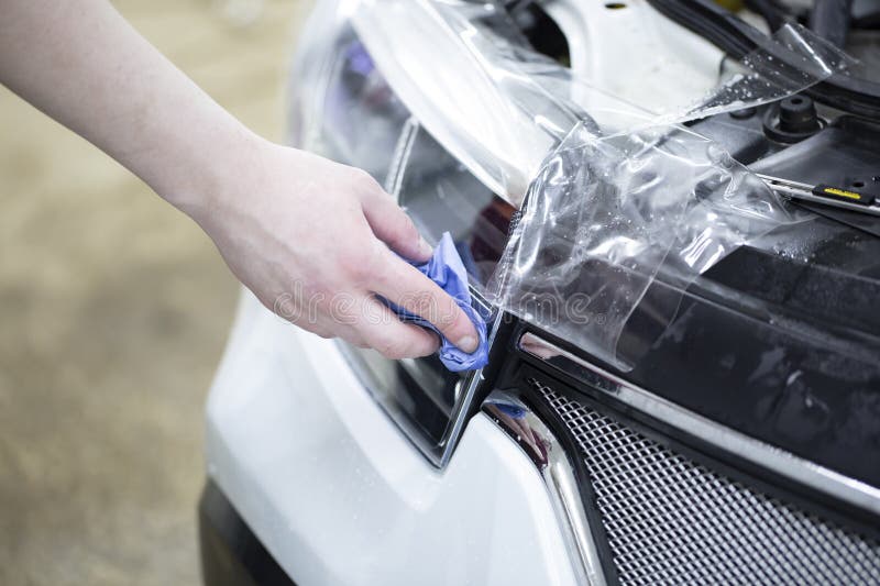 Installation of a Protective Film for Car Paint.the Workers Install a ...