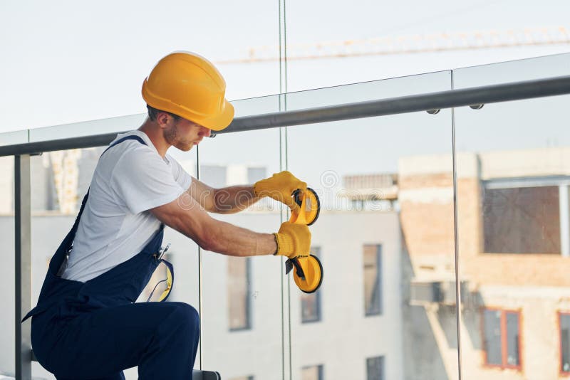 Installation of Windows. Young Man Working in Uniform at Construction ... Installation of Windows. Young Man Working in Uniform at Construction ...