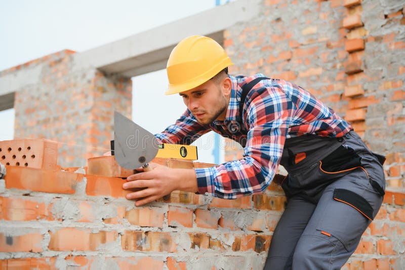 Installing Brick Wall. Construction Worker in Uniform and Safety ...