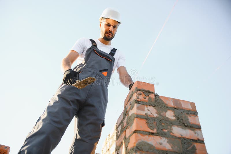Installing Brick Wall. Construction Worker in Uniform and Safety ...