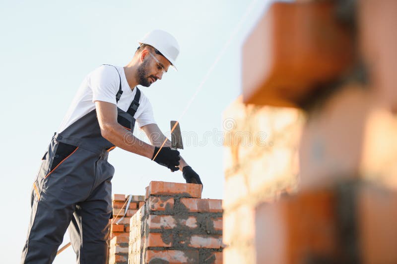 Installing Brick Wall. Construction Worker in Uniform and Safety ...
