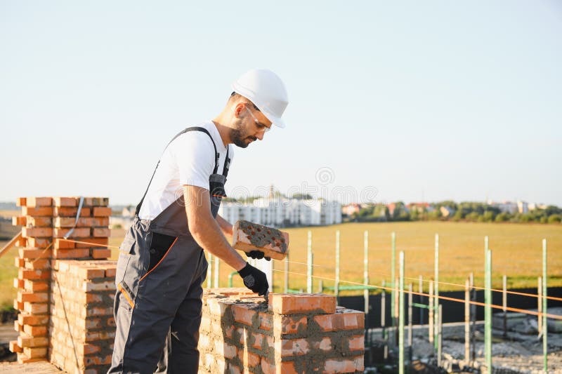 Installing Brick Wall. Construction Worker in Uniform and Safety ...