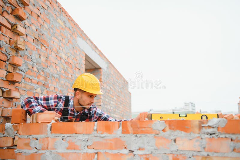 Installing Brick Wall. Construction Worker in Uniform and Safety ... Installing Brick Wall. Construction Worker in Uniform and Safety ...
