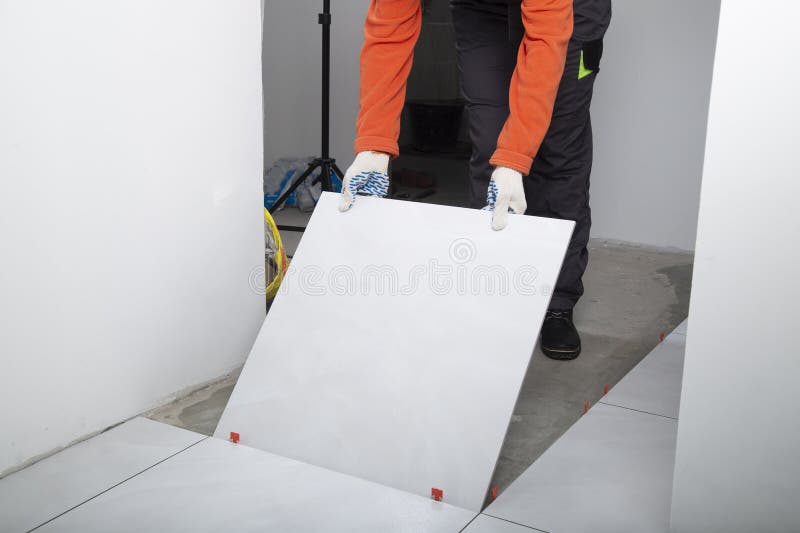 Installing Ceramic Tiles on the Floor. a Worker Installs Ceramic Tiles ...