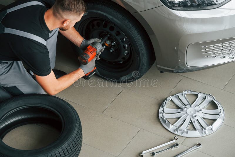 Installing New Tire. Man in Uniform is Working in the Autosalon at ...