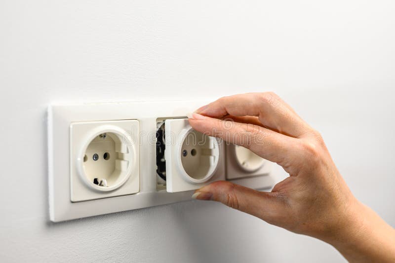 Installing a White AC Wall Socket with a Screwdriver on a White Wall ...