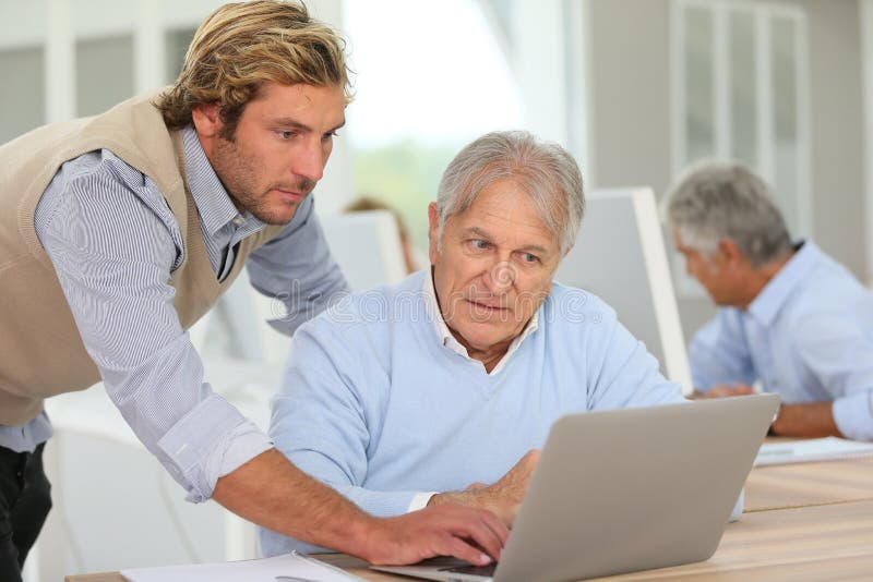 Instructor Assisting Senior Man in Class Stock Image - Image of ...