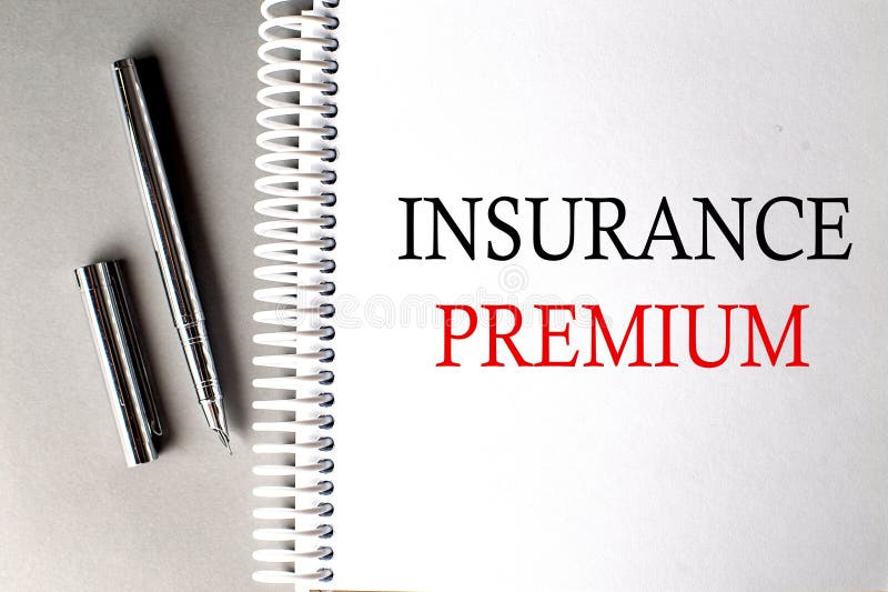 INSURANCE PREMIUM Text on a Notebook with Pen on Grey Background Stock ...