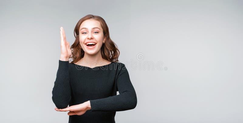 Intelligent Enthusiastic Young Woman Raises Her Hand Up To Attract