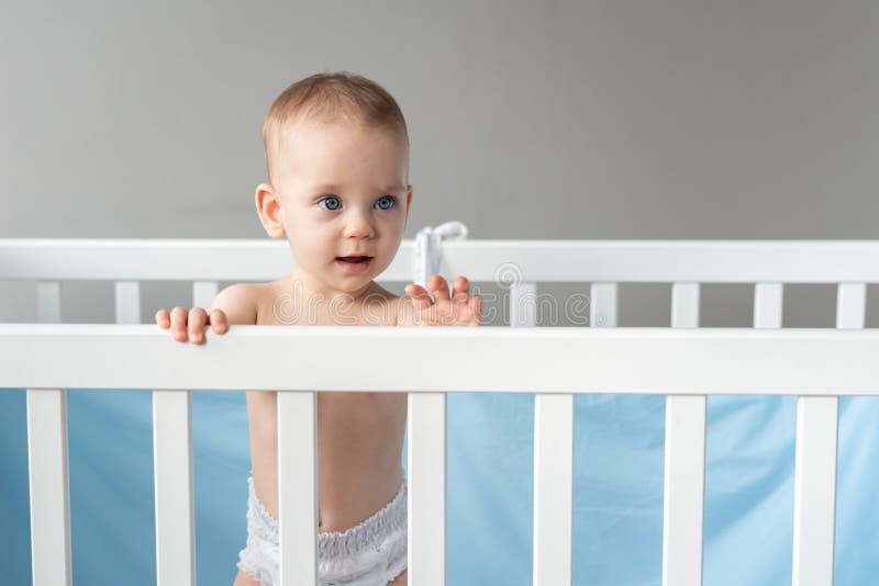 Interested Baby Leaning on the Back of a Wooden Crib Stock Photo ...