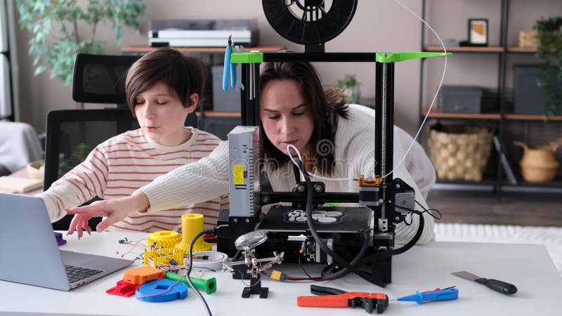 Mother Helping Her Son with Homework Using Laptop and 3D Printer Stock ...