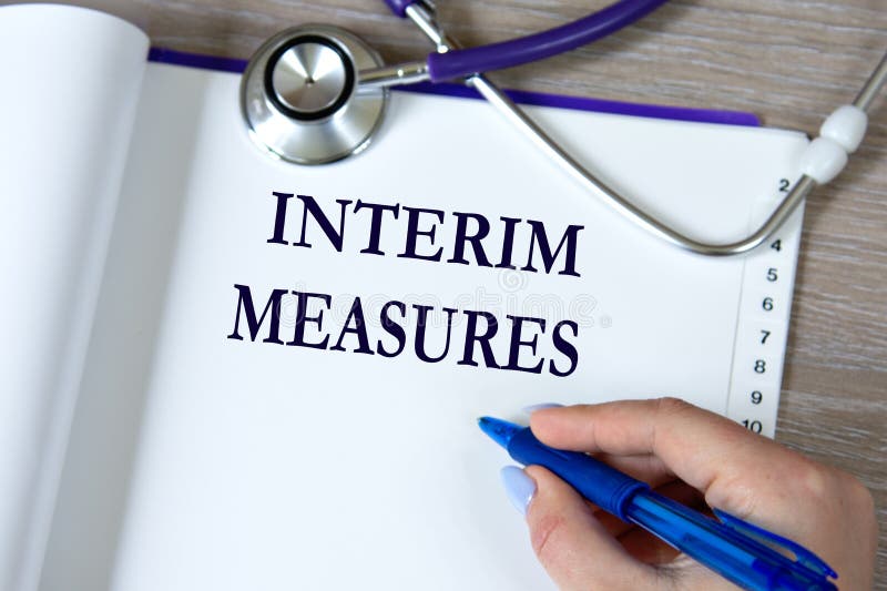 INTERIM MEASURES - Word in a Notebook Against the Background of a ...
