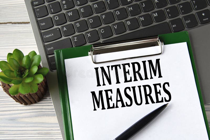 INTERIM MEASURES - Words on a White Sheet on the Background of a Laptop ...