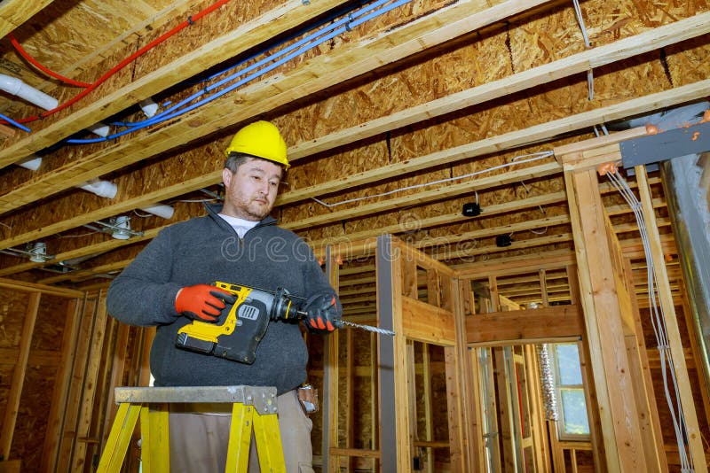 Interior Frame of a New House Under Construction Worker Drills Hole ...