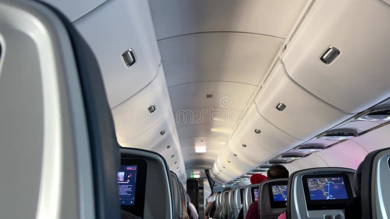 Interior View of a Narrow Airplane Cabin with Passengers Seated in ...