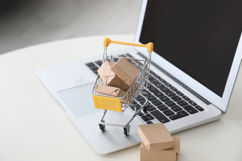 Internet Shopping. Laptop and Small Cart with Boxes on White Table ...
