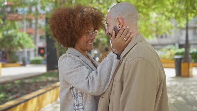 Interracial Couple Embracing Joyfully In A Sunny Urban Park Stock