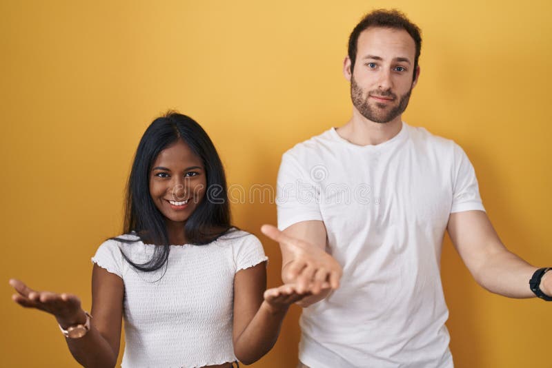 Interracial Couple Standing Over Yellow Background Smiling Cheerful