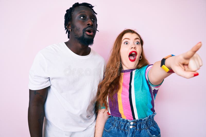 Interracial Couple Wearing Casual Clothes Pointing With Finger