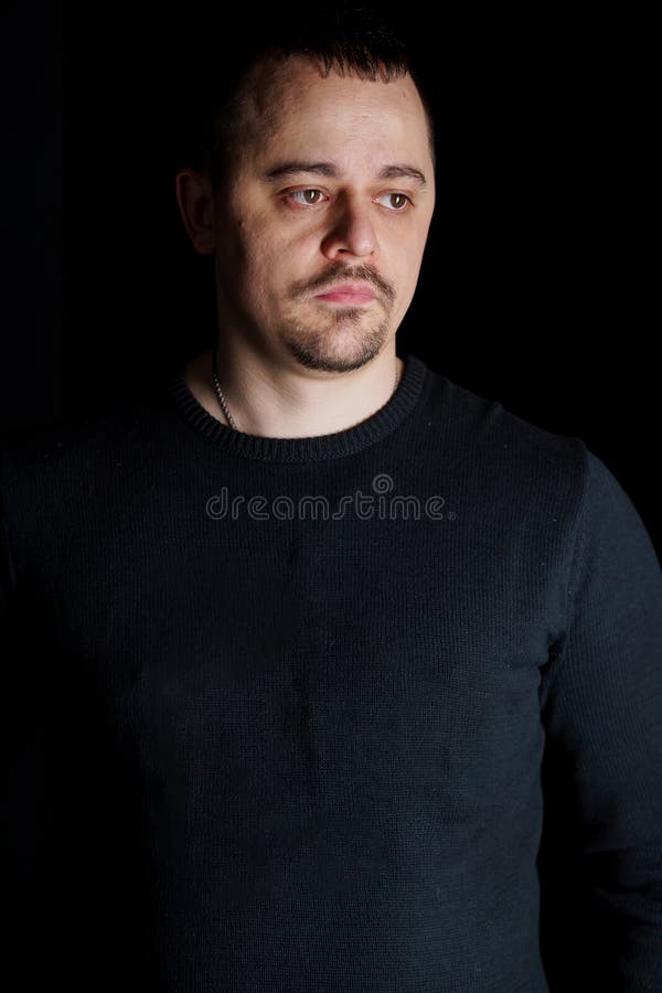 Introspective Man in a Black Sweater Against a Dark Background Stock ...