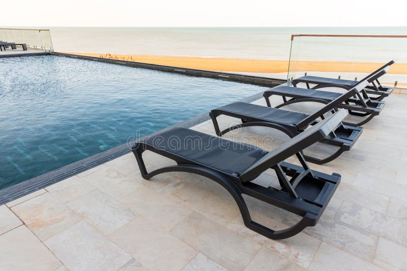 An Inviting Infinity Pool with Reclining Lounge Chairs by the Seaside ...