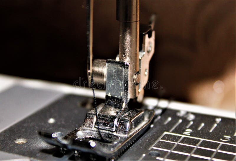 The Iron Foot of a Grey Sewing Machine with Black Thread is Shown in ...