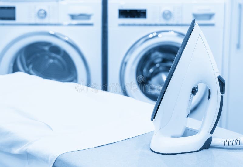 Iron on Ironing Board with White Shirt in Laundry Room Stock Photo ...