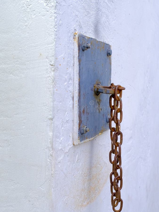 An Iron Ring with a Rusty Chain is Driven into the White Concrete Wall ...