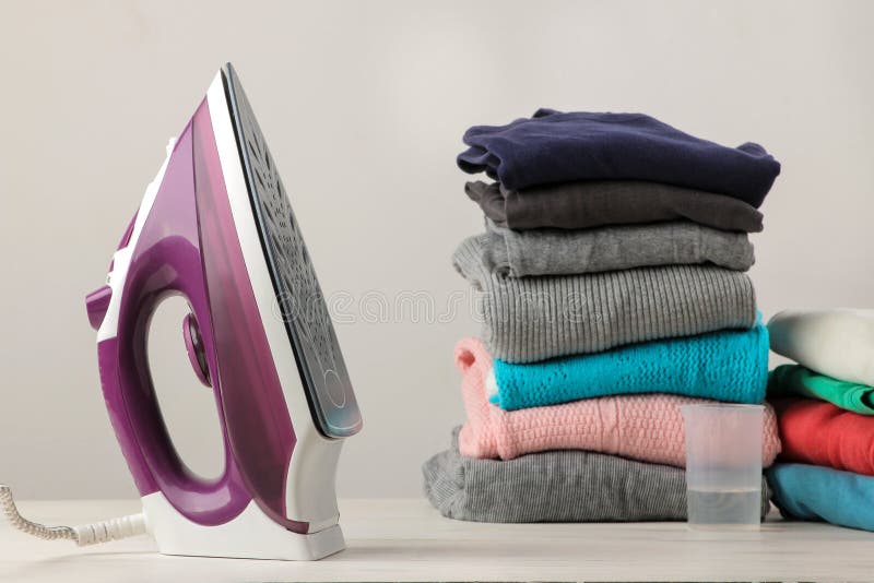 Iron and a Stack of Colored Clothes on a White Background. Ironing of ...