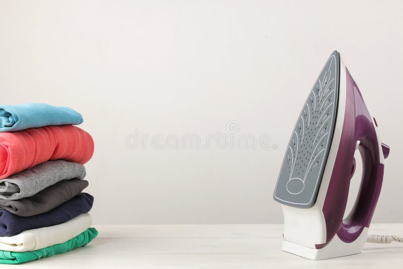 Iron and a Stack of Colored Clothes on a White Background. Ironing of ...