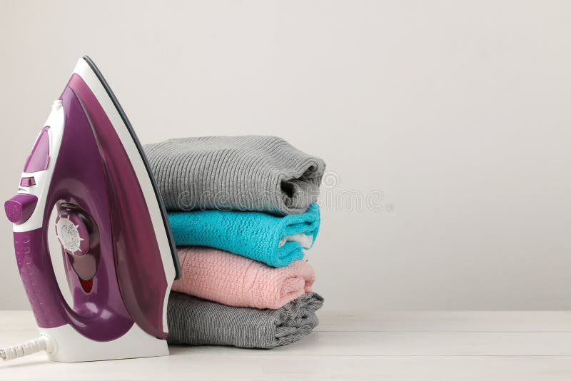 Iron and a Stack of Colored Clothes on a White Background. Ironing of ...