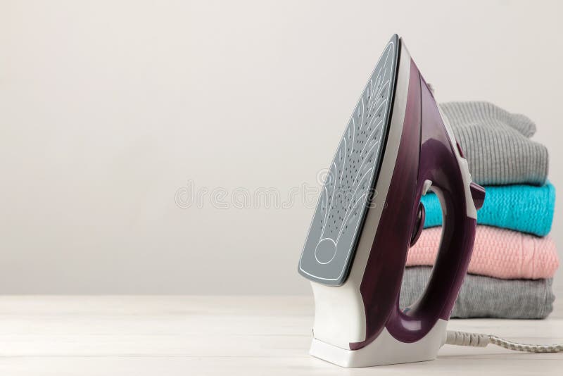 Iron and a Stack of Colored Clothes on a White Background. Ironing of ...