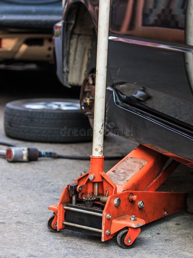 Jacking Up a Car with the Emergency Jack for Changing Car Tire Stock ...